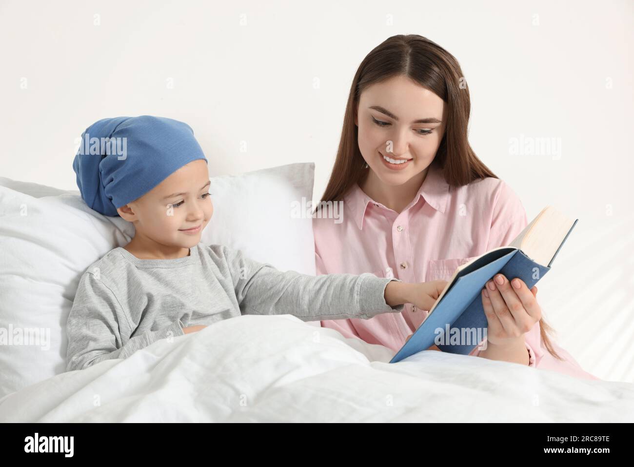 Childhood cancer. Mother and daughter reading book in hospital Stock ...