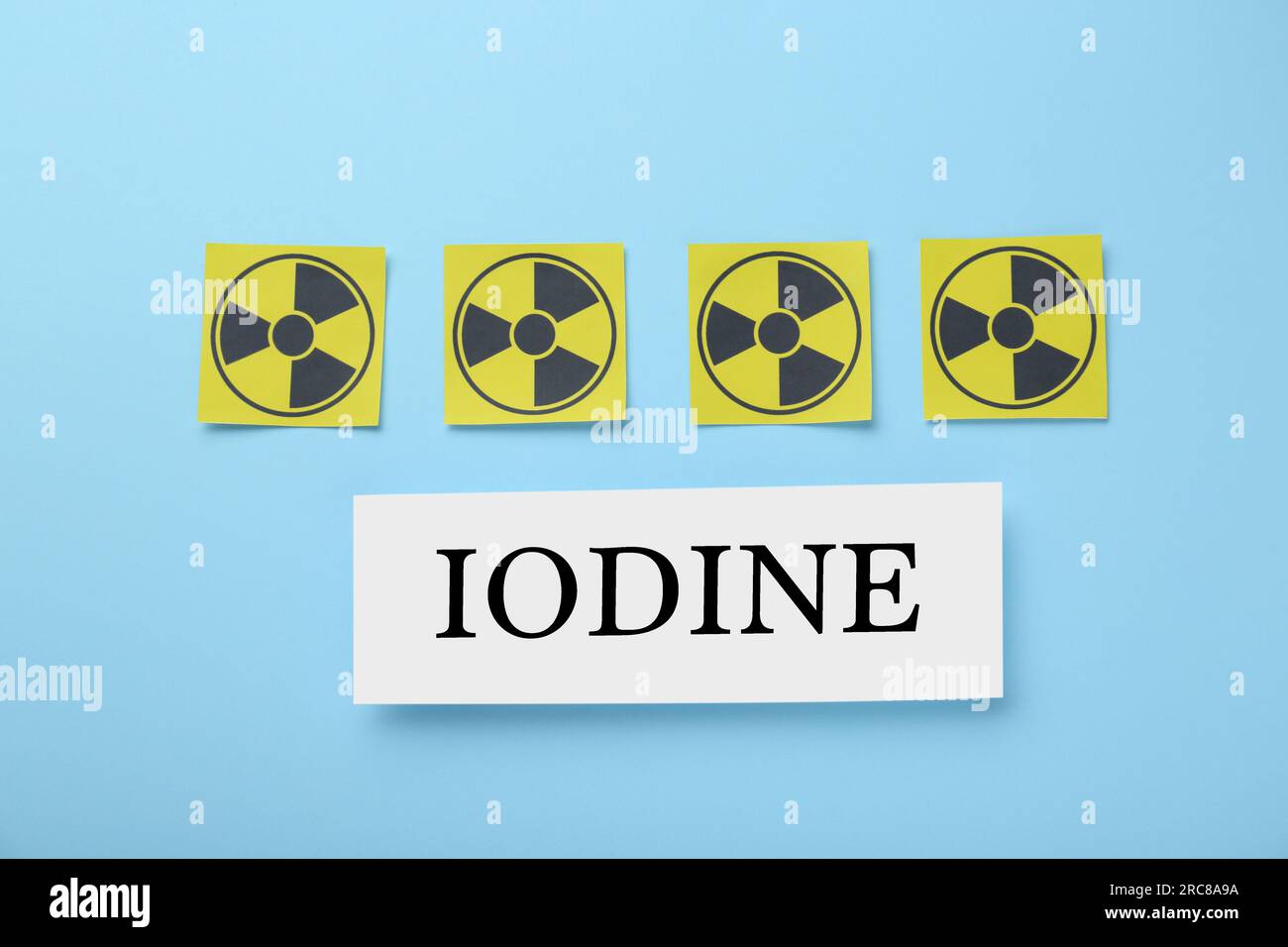 Paper note with word Iodine and radiation signs on light blue ...