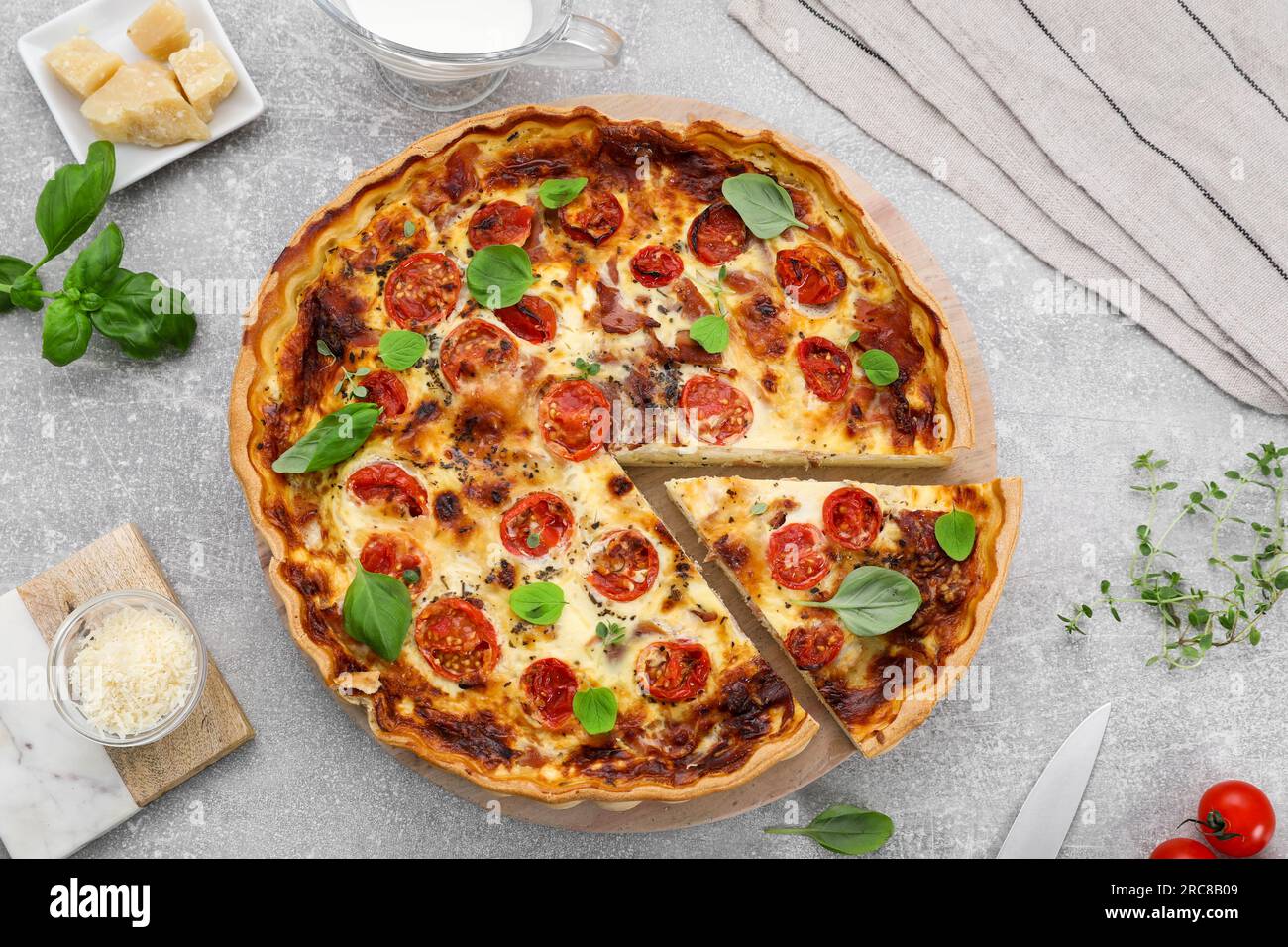 Cut delicious homemade quiche with prosciutto and ingredients on light ...