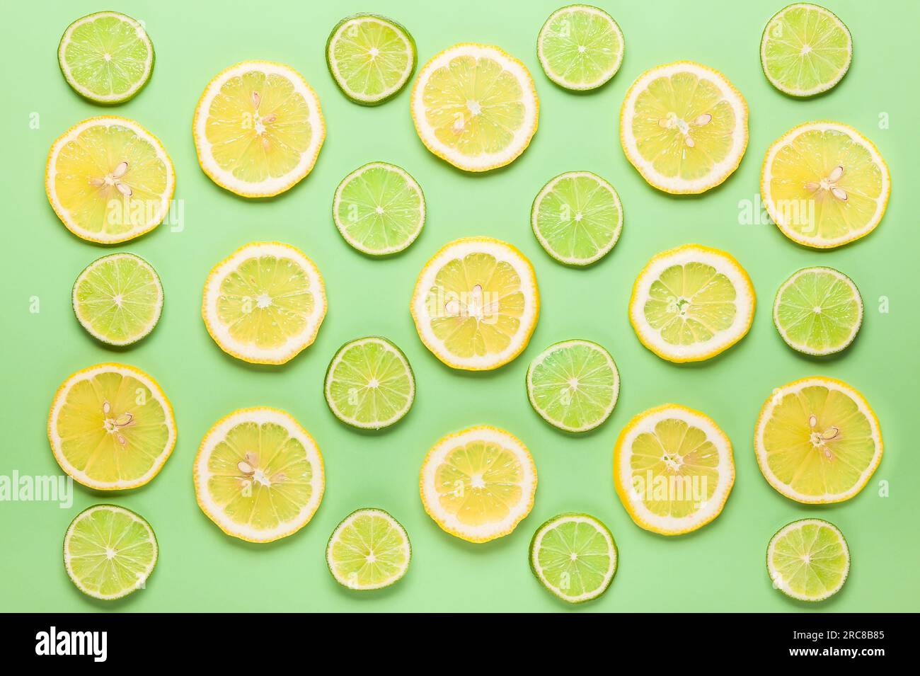 Slices of fresh lemon and lime pattern on pastel green background in ...