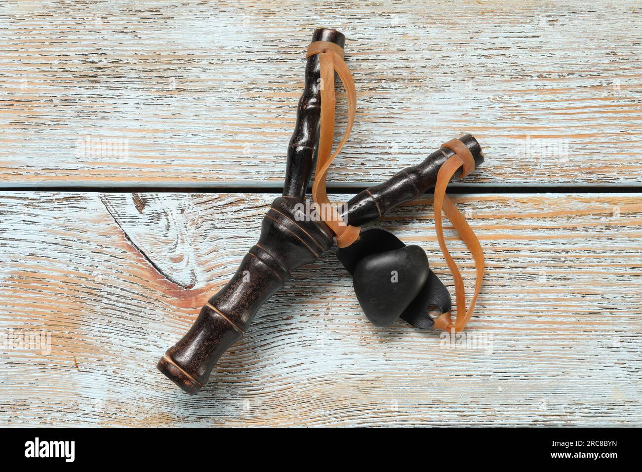 Black slingshot with pebble on old light blue wooden table, top view ...
