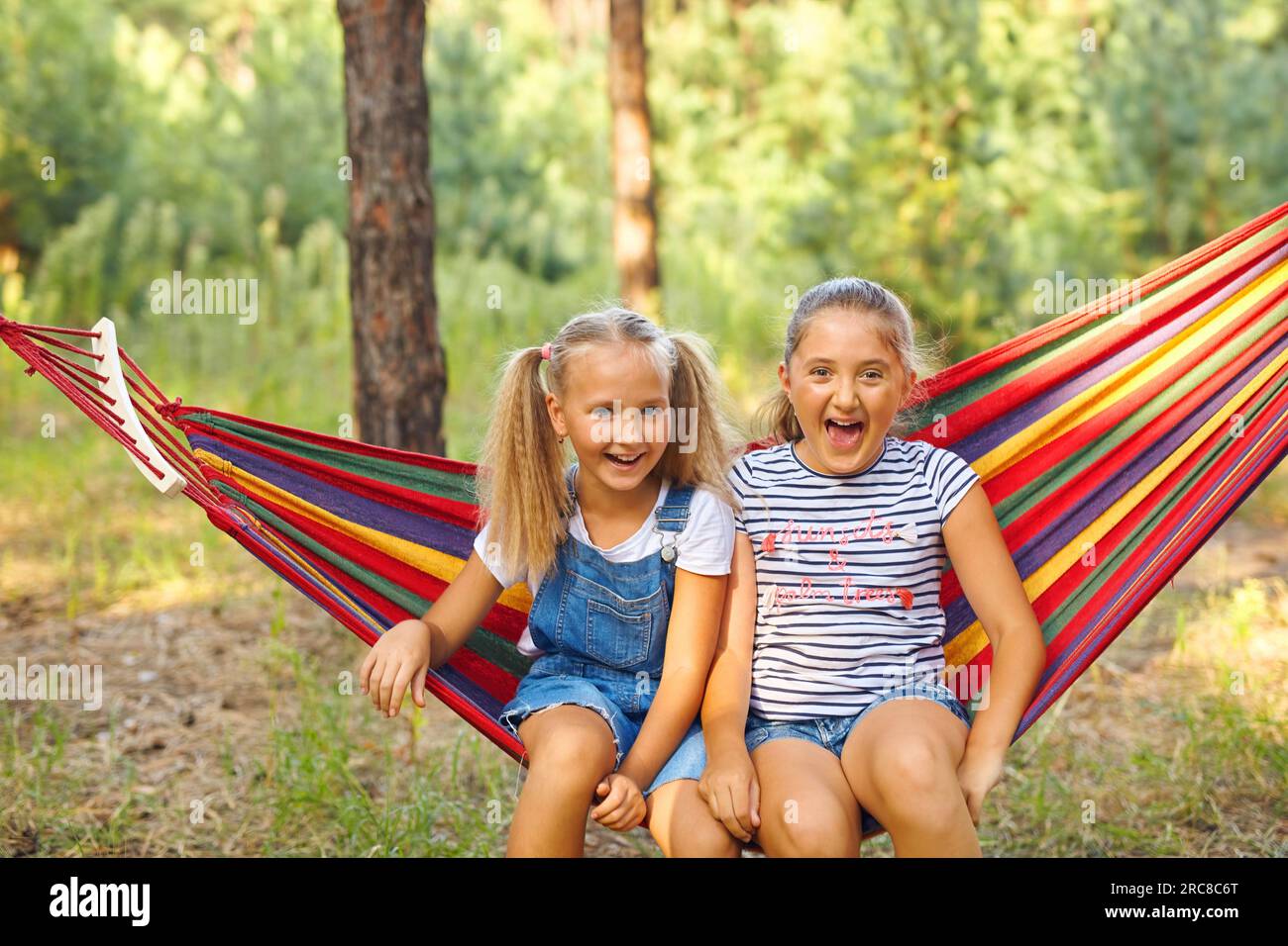 Kids relax in colorful rainbow hammock. Hot day garden outdoor fun ...