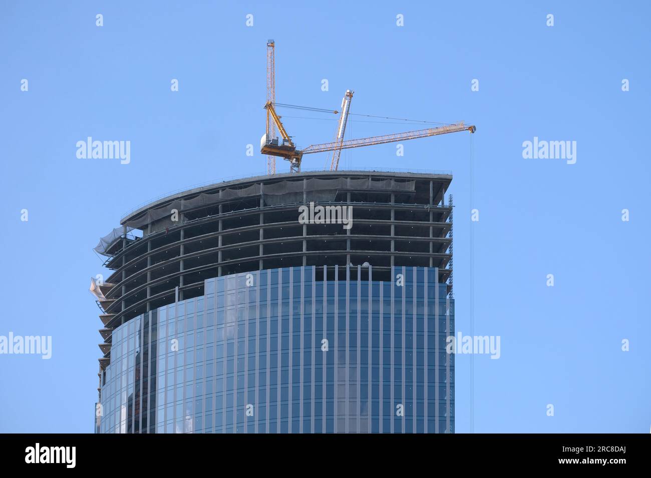 Yellow hoisting tower crane on the top section being construction of ...