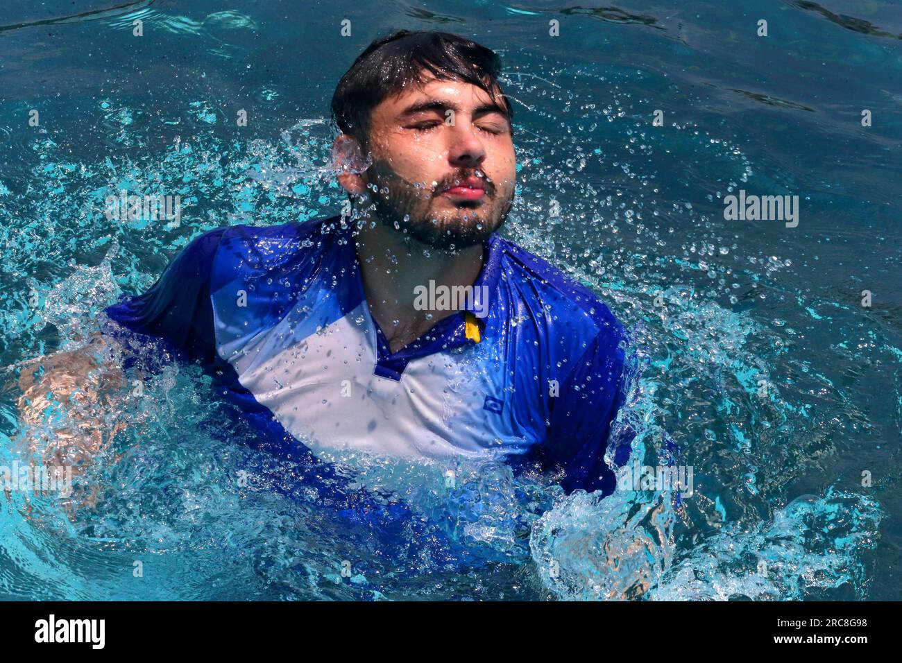 A Pakistani man cools himself off into a commercial swimming pool as ...