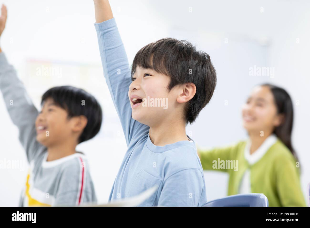 An elementary school student cheerfully raises his hand Stock Photo - Alamy
