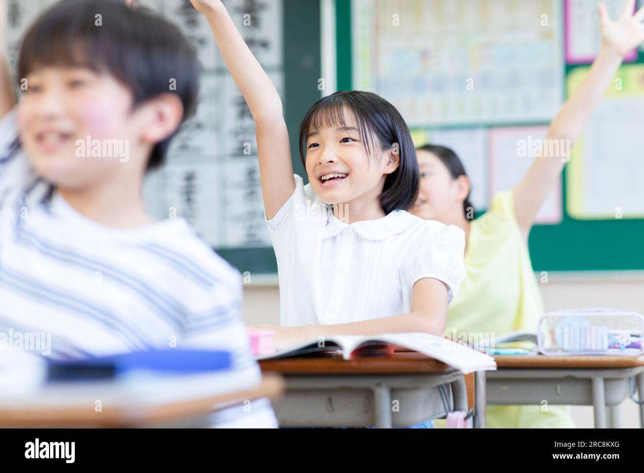 Elementary school students raising their hands during class Stock Photo - Alamy