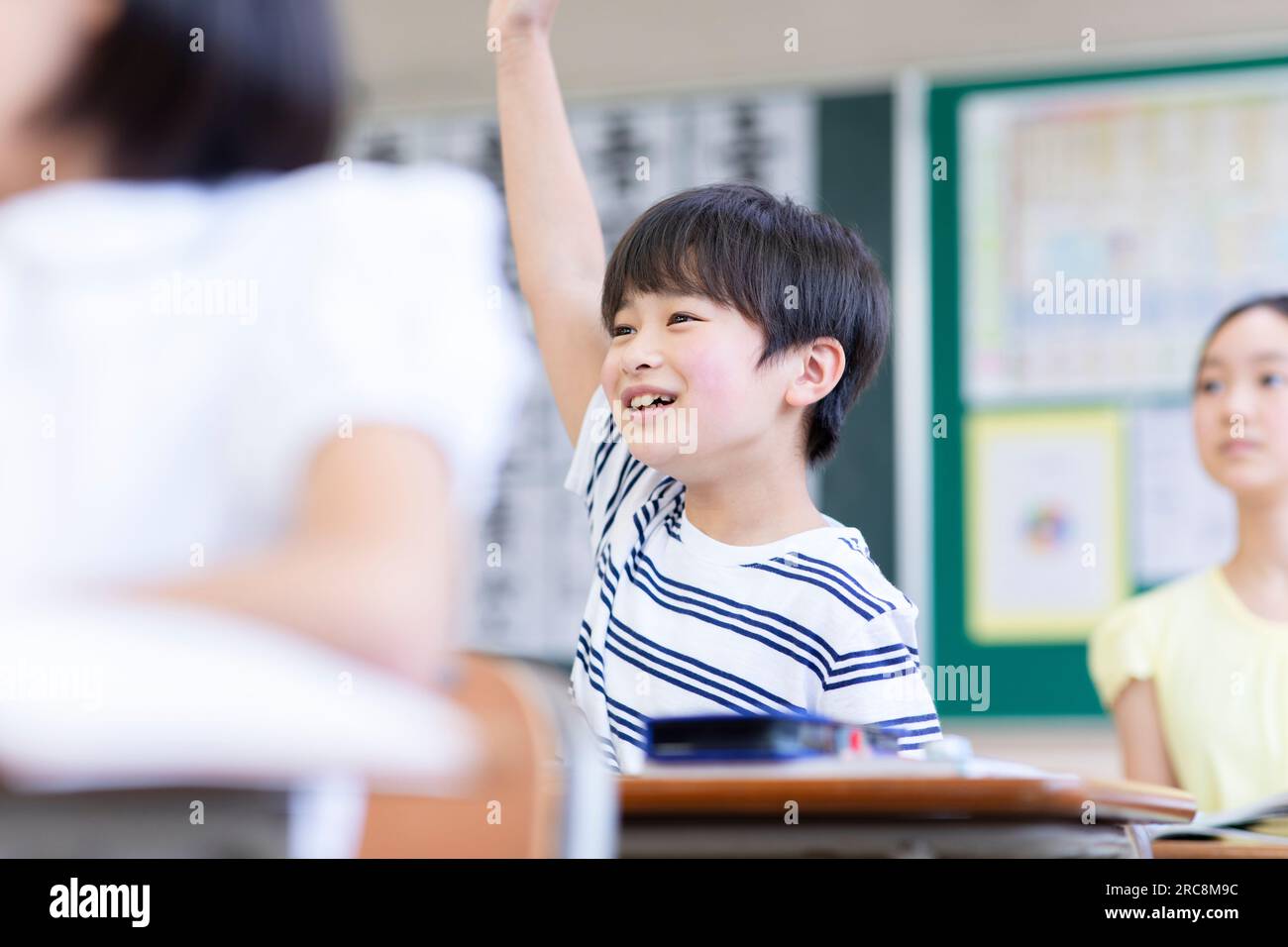 An elementary school student raises his hand during class Stock Photo ...