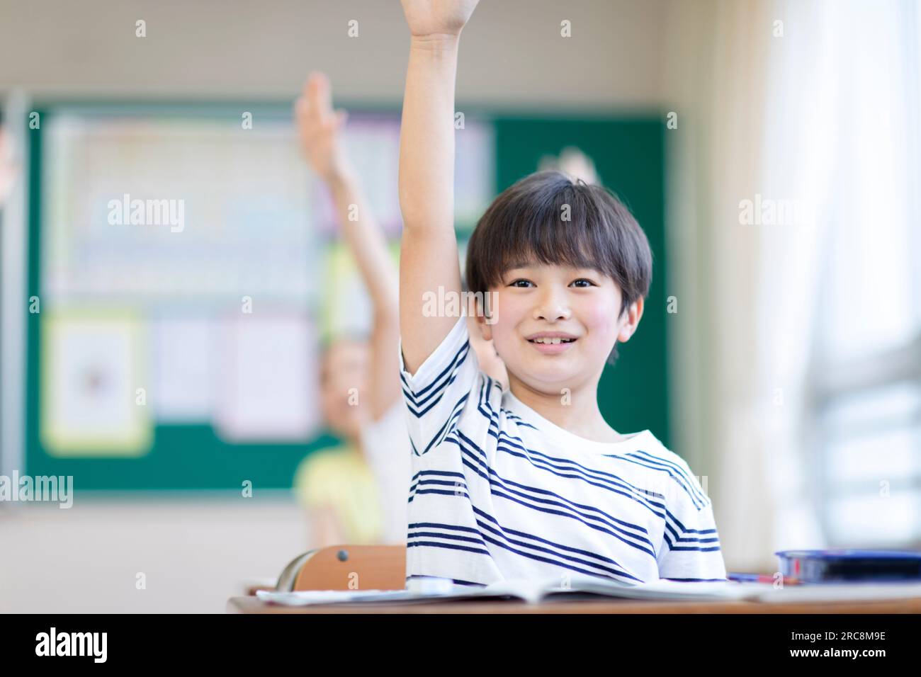 Elementary school students raising their hands during class Stock Photo ...