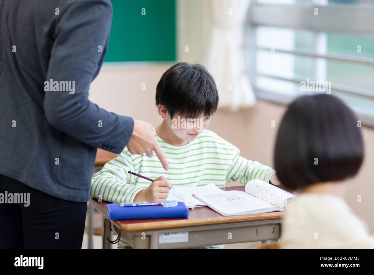 A boy being taught by his teacher during class Stock Photo - Alamy