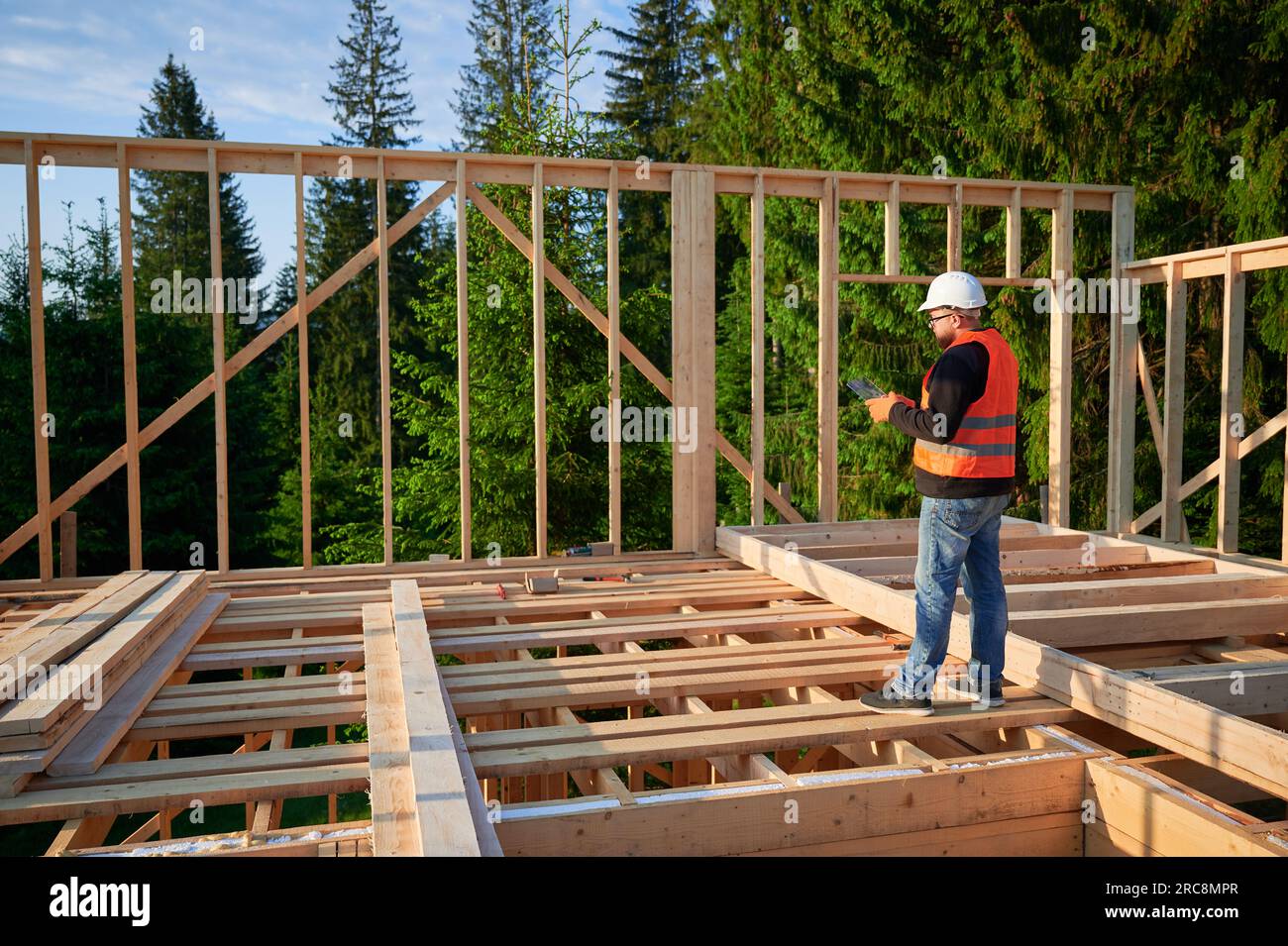 Carpenter constructing wooden two-story frame house near the forest ...