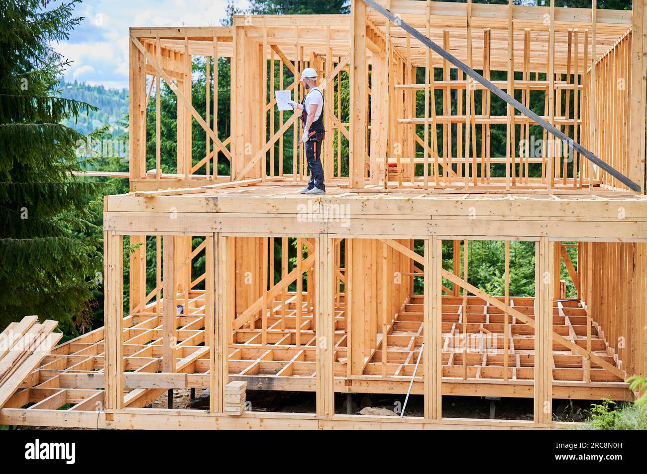Inspector examining construction plan of wooden two-story building. Man ...