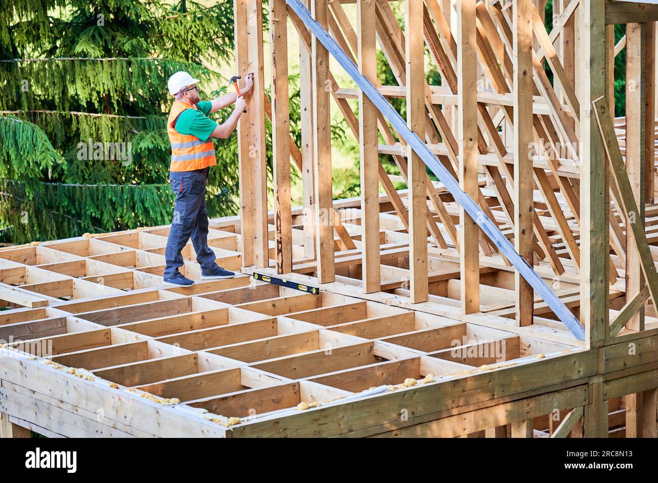 Carpenter constructing two-story wooden frame house near the forest ...