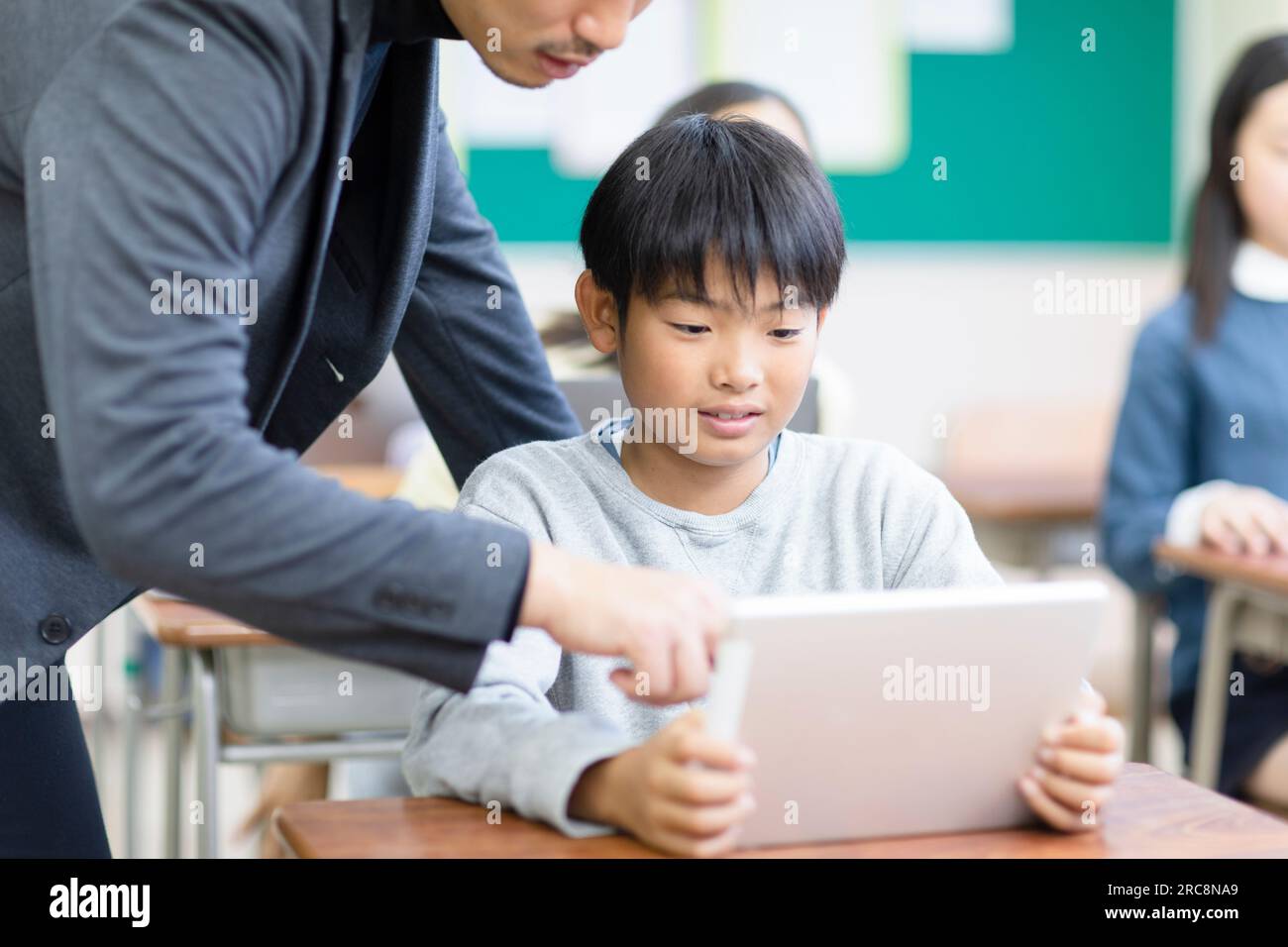 Elementary school students and their teacher studying on a tablet PC ...