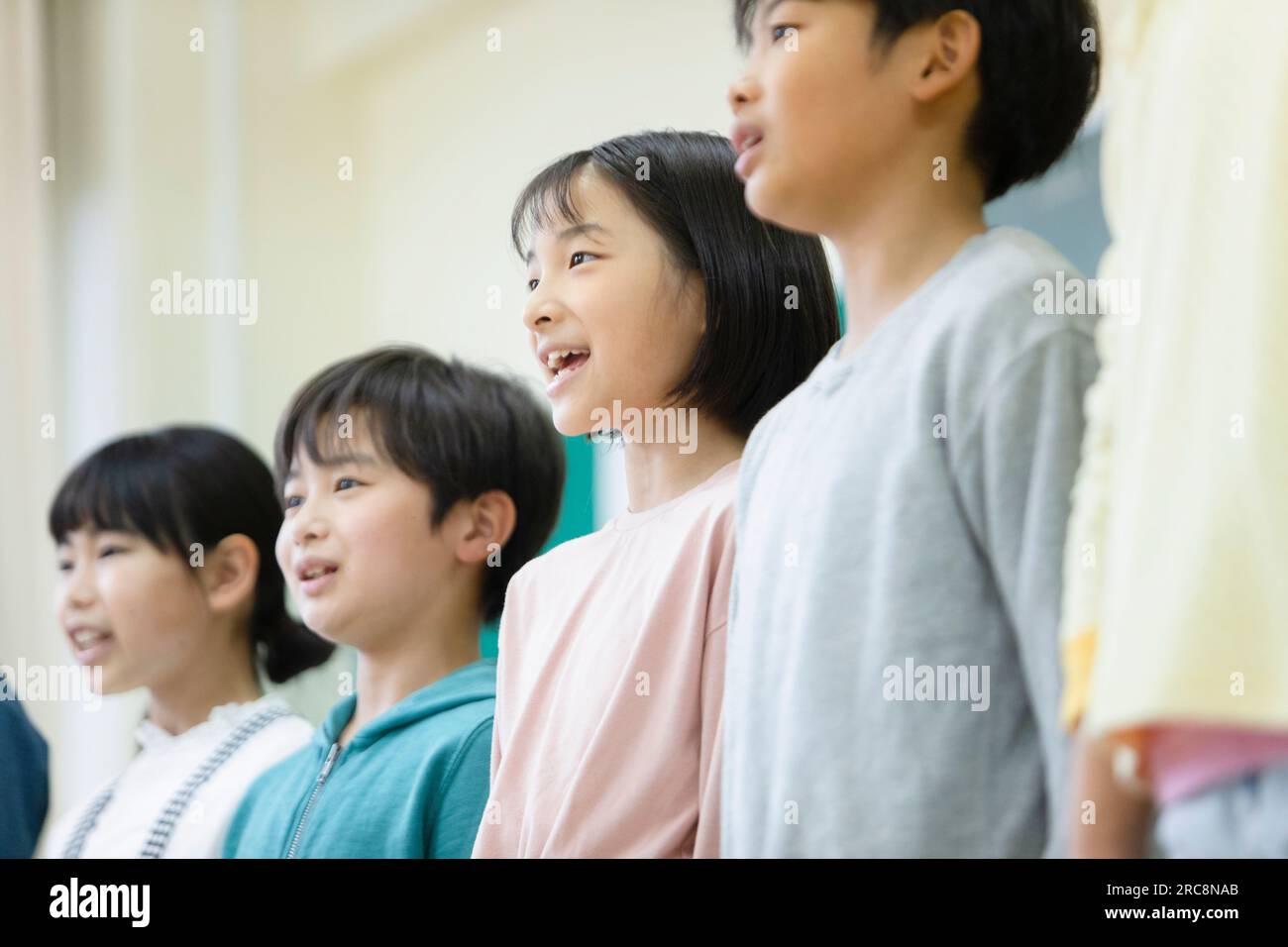 Elementary school students singing a song in front of the blackboard ...