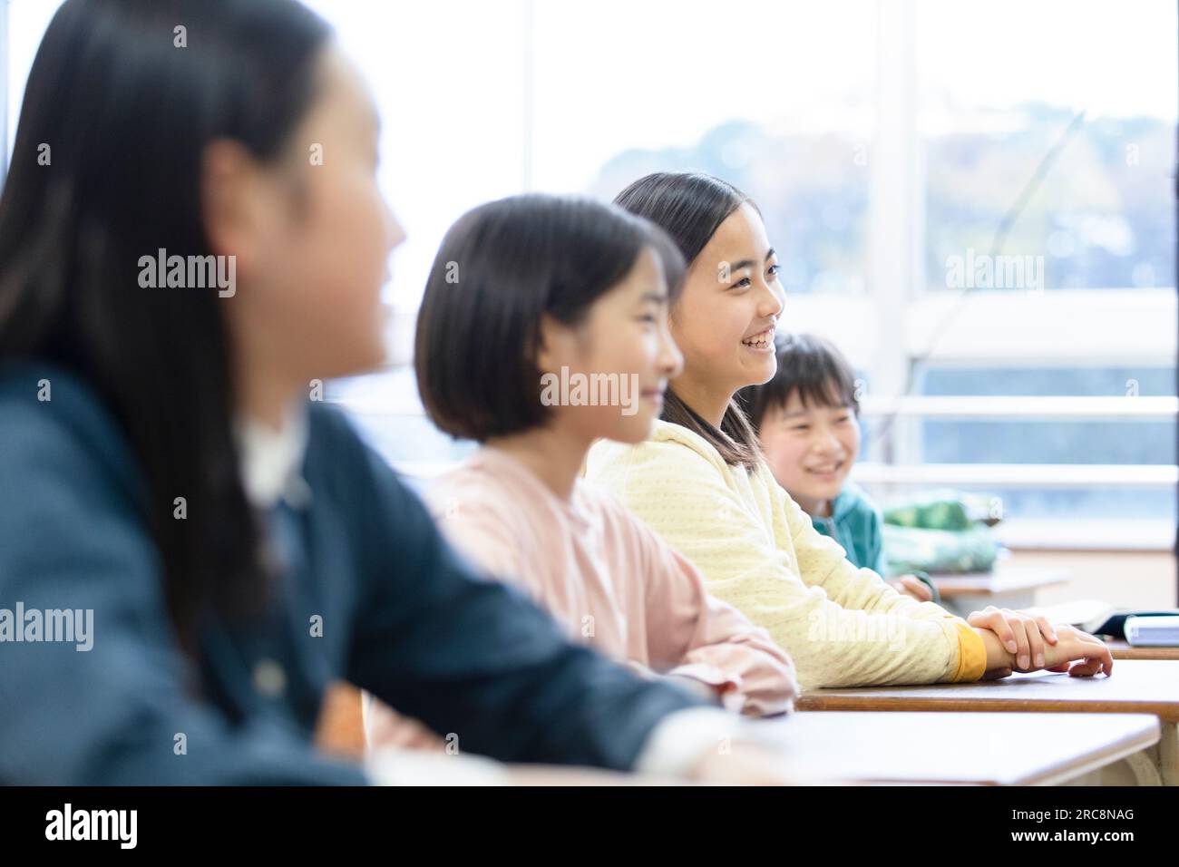 Elementary school students listening with smiles Stock Photo - Alamy