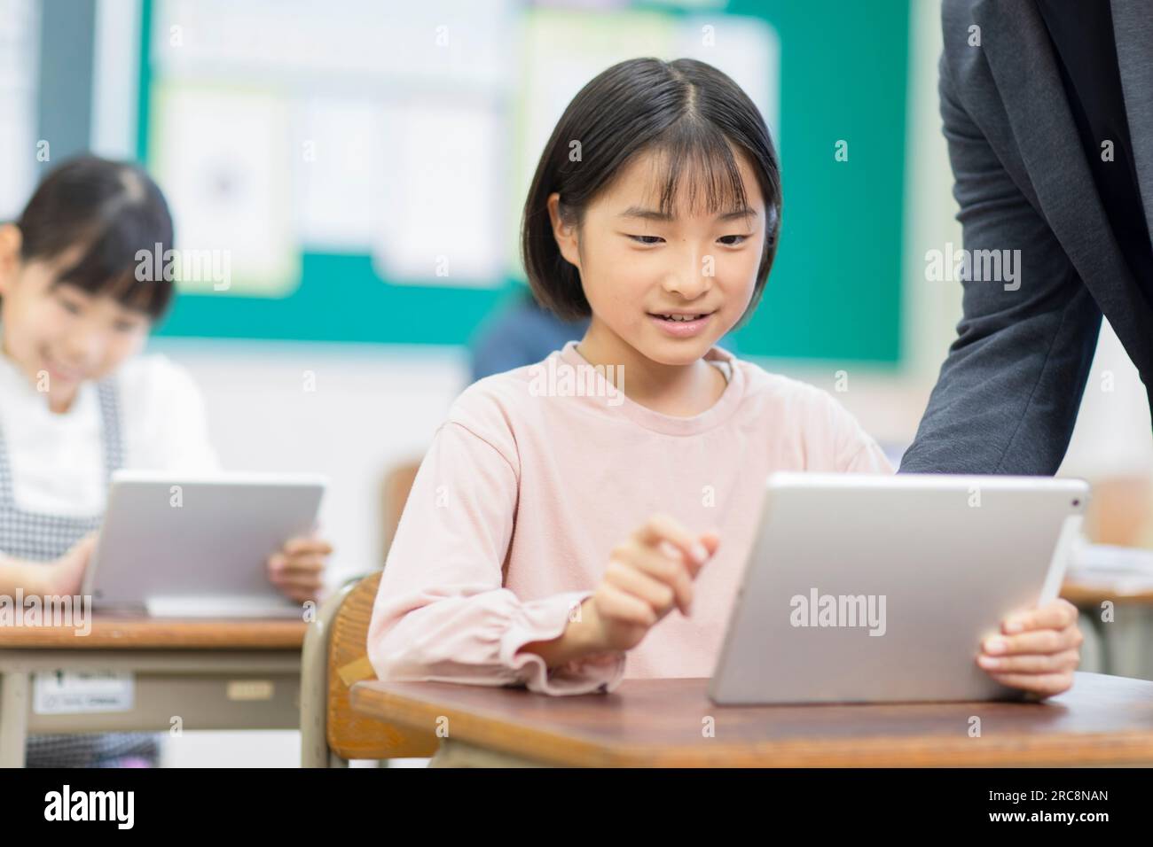 Elementary school students and their teacher studying on a tablet PC ...