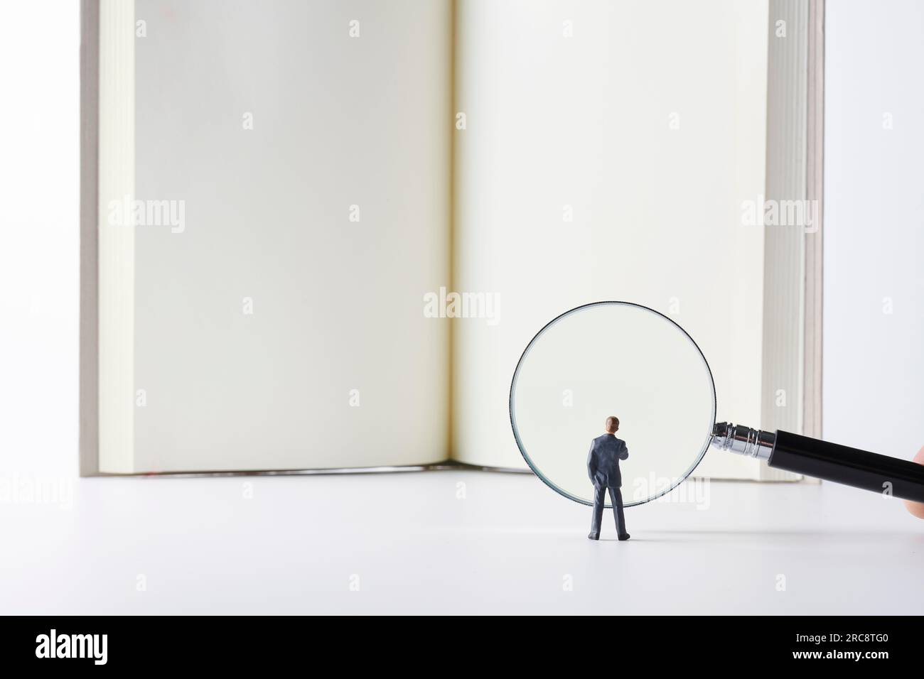 Businessman reading a book with magnifying glass Stock Photo - Alamy