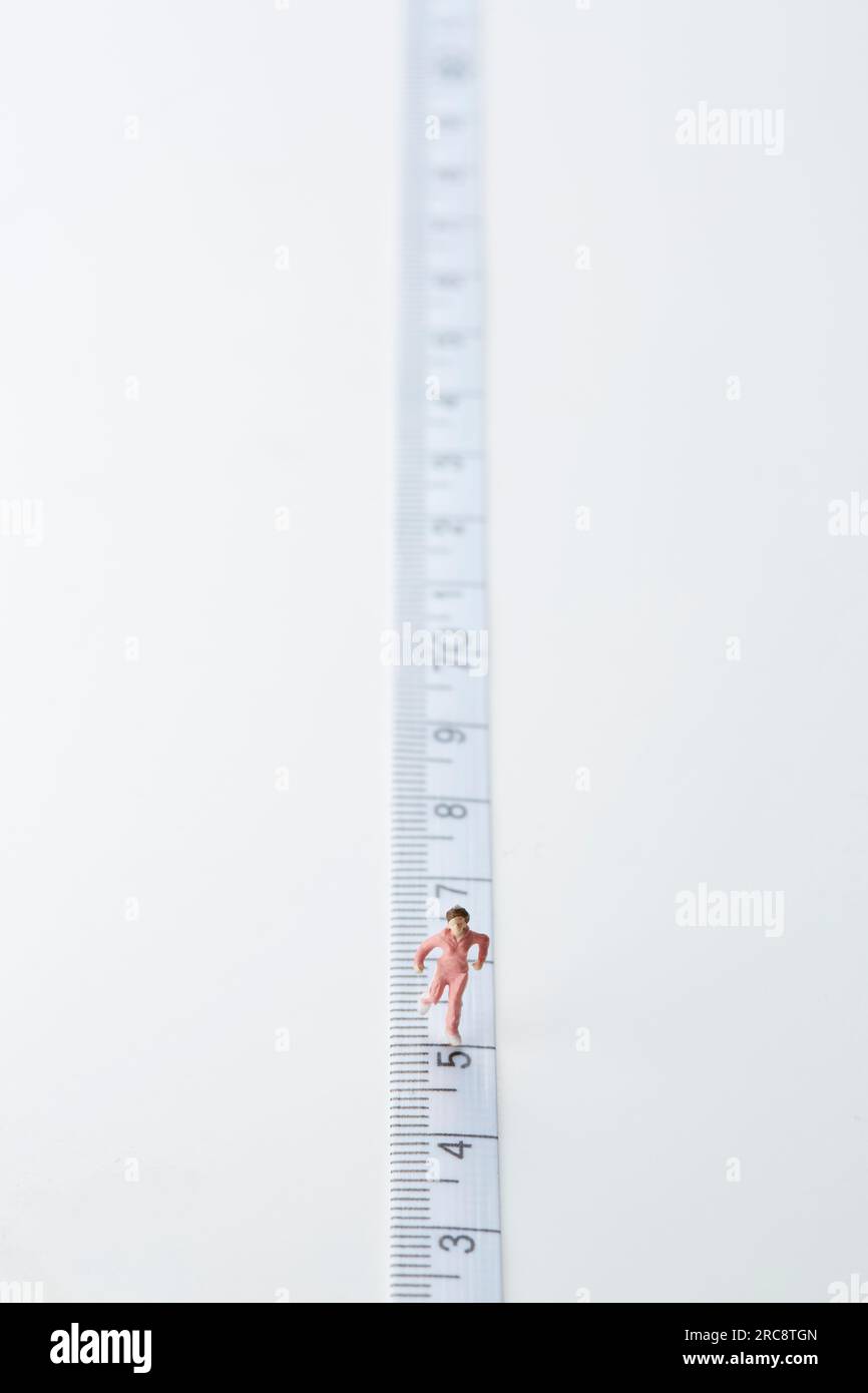 Miniature doll woman running on a measuring tape Stock Photo - Alamy