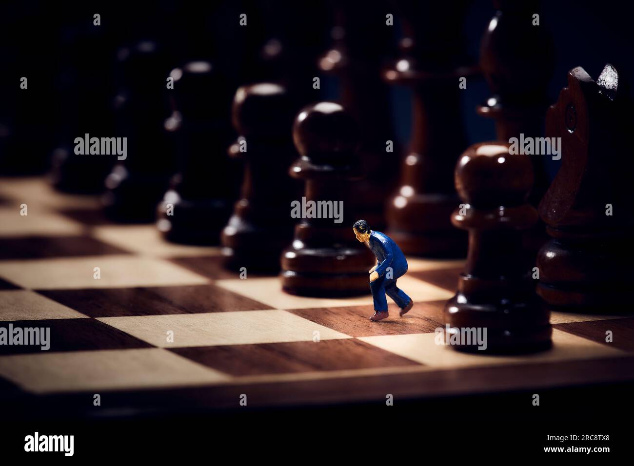 Miniature person in suit with pieces on chess board Stock Photo - Alamy
