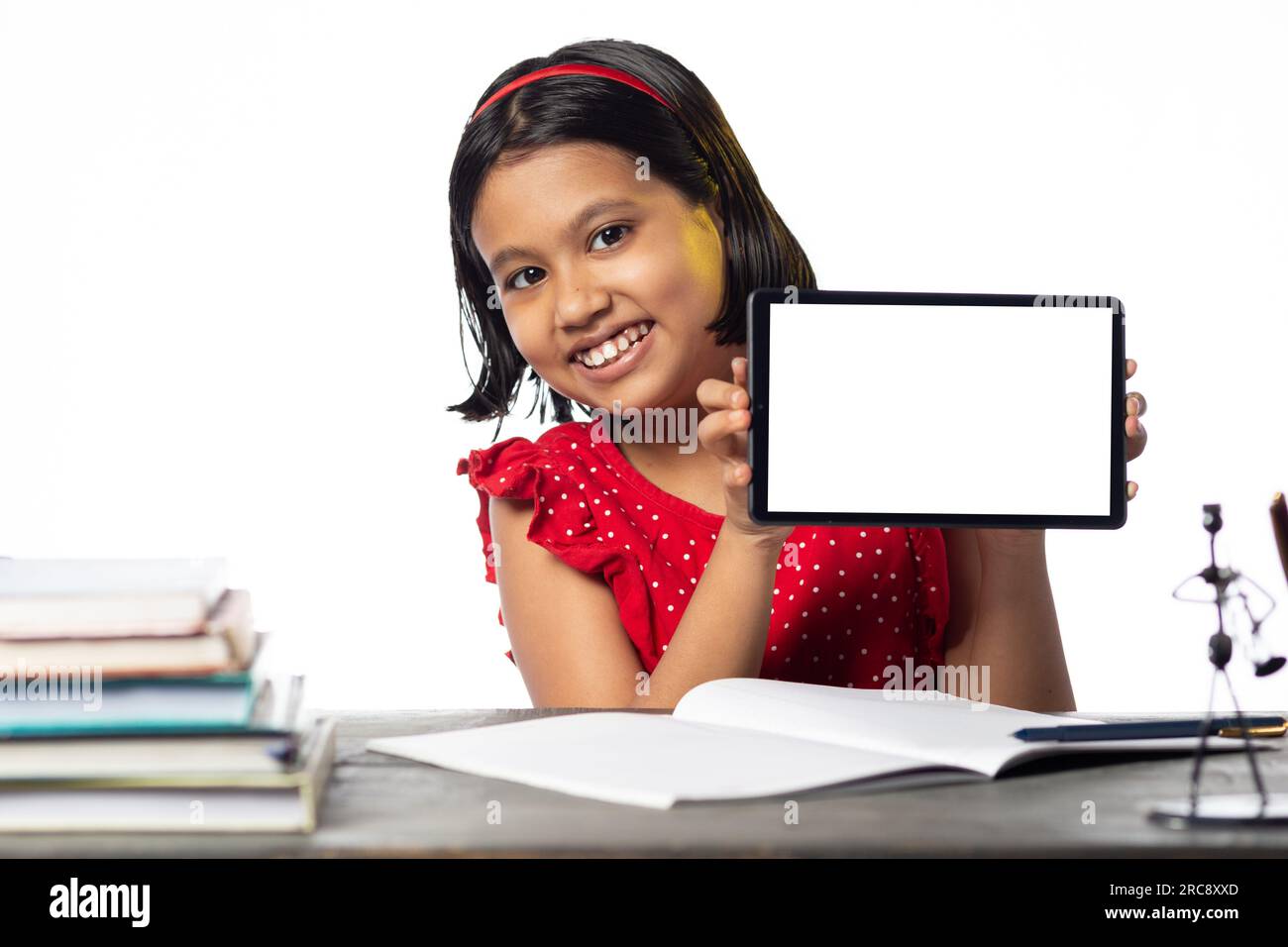 A pretty beautiful Indian girl child studying and showing blank screen ...