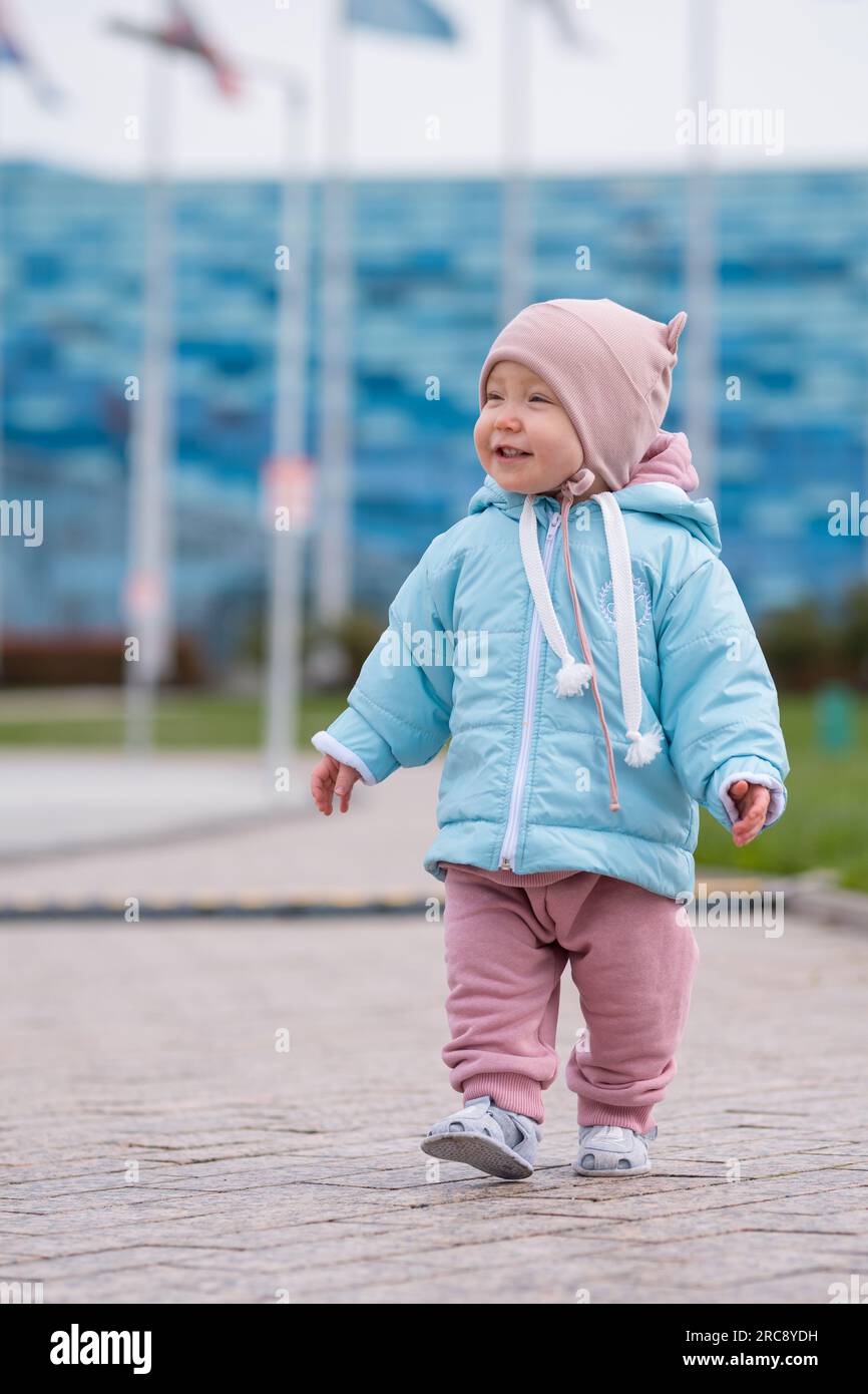 Toddler girl in pink hat walking alone on city sidewalk Stock Photo - Alamy