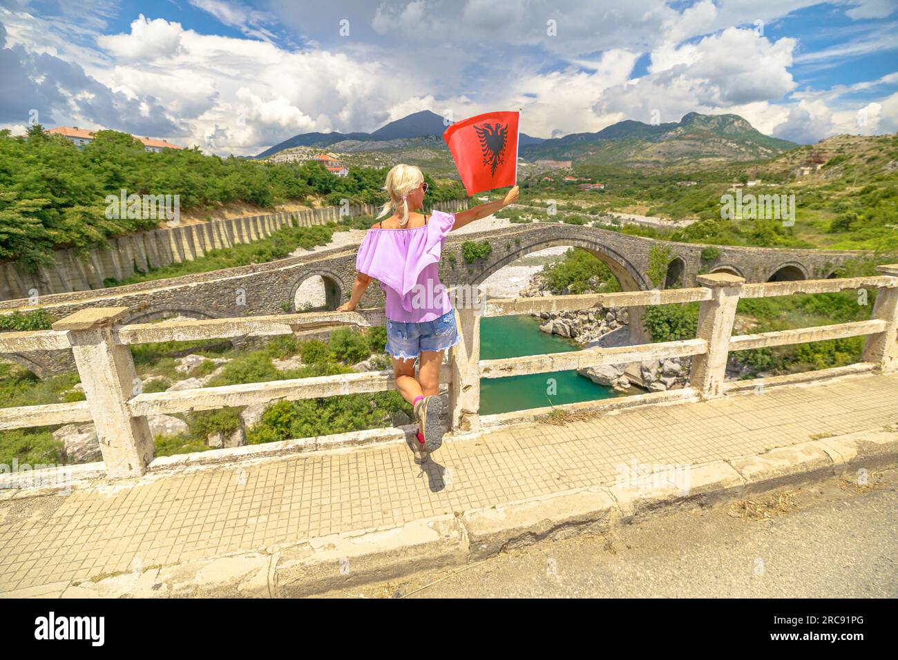A woman visiting Mesi Bridge with Albania flag. Mesi Bridge is an ...