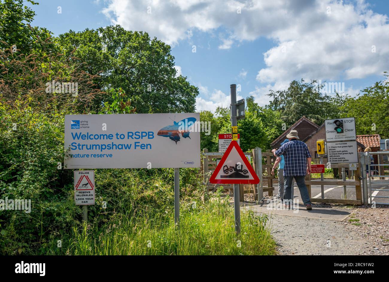 Adults crossing a railway footpath crossing to the RSPB Strumpshaw ...