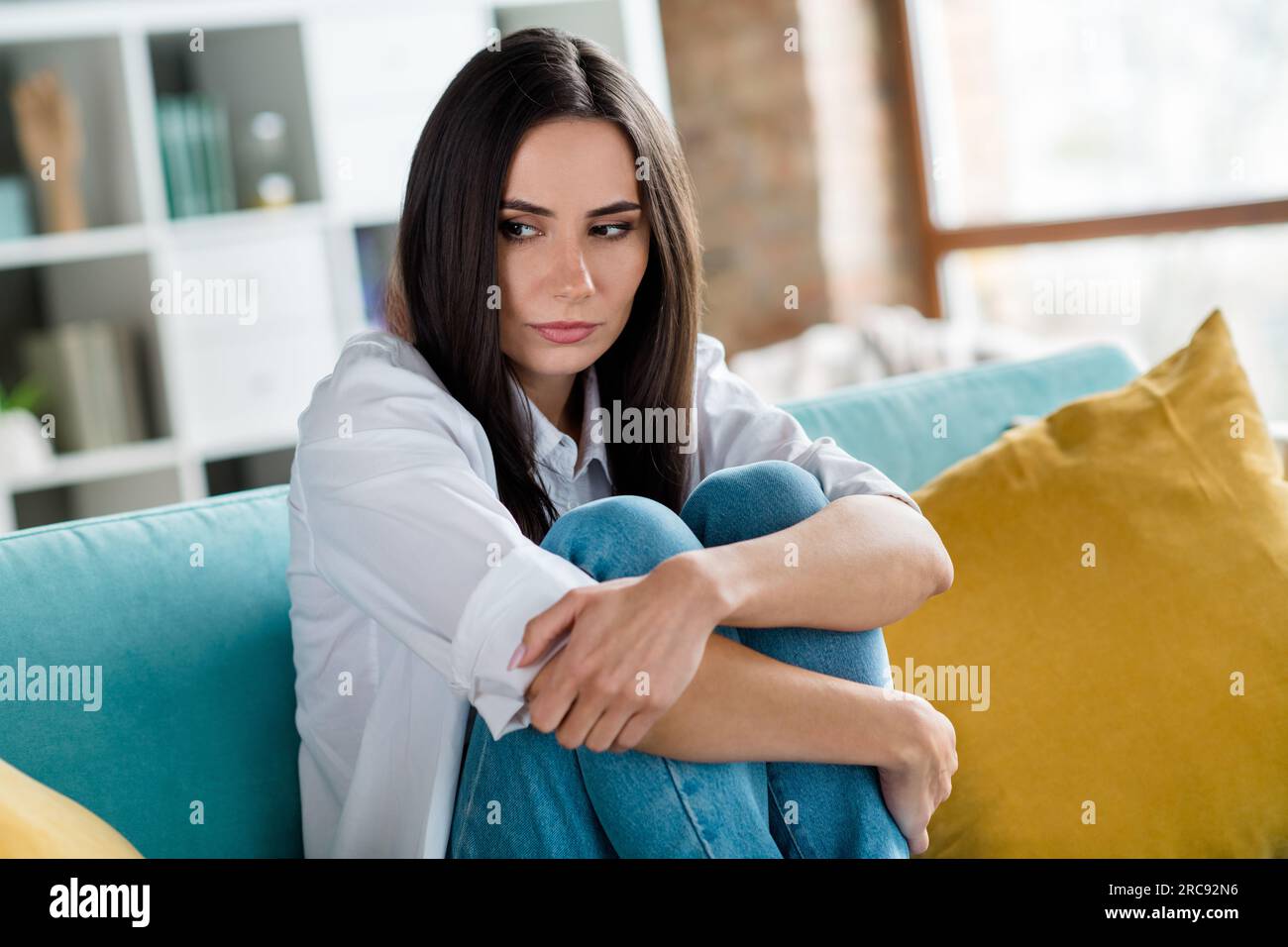 Photo of unsatisfied pretty person sitting couch hands hold legs bad ...