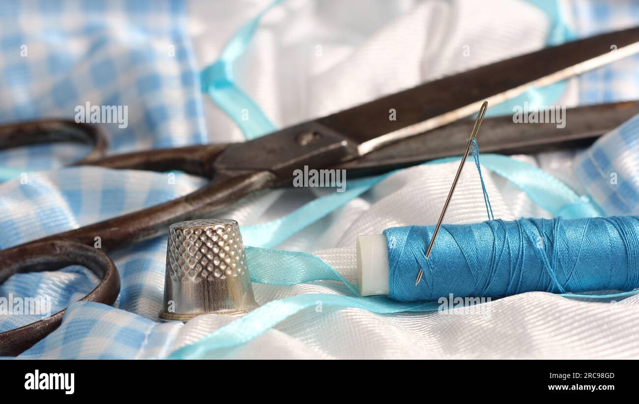 Spool of Blue Thread, Thimble and Needle on Vintage Blue and White ...