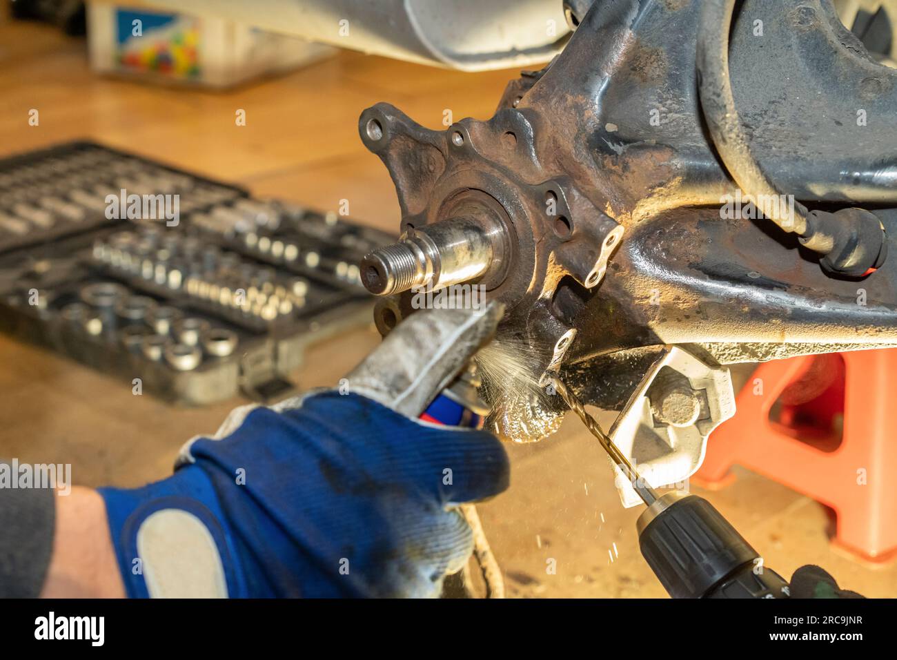 Old rusty wheel hub bearing repairing. One car mechanic drills a thread ...