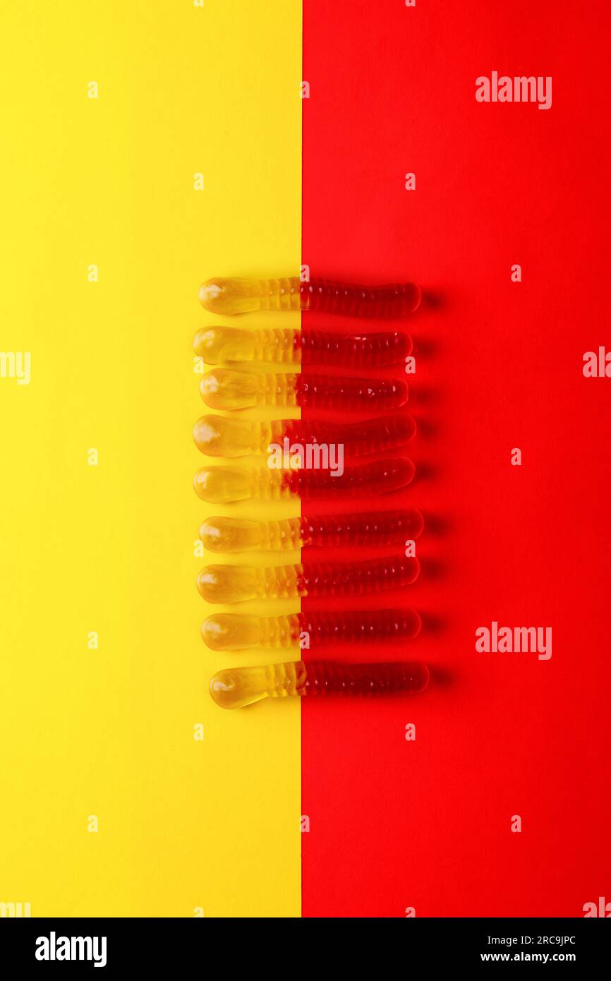 Gummi worms isolated on plain red and yellow background Stock Photo - Alamy