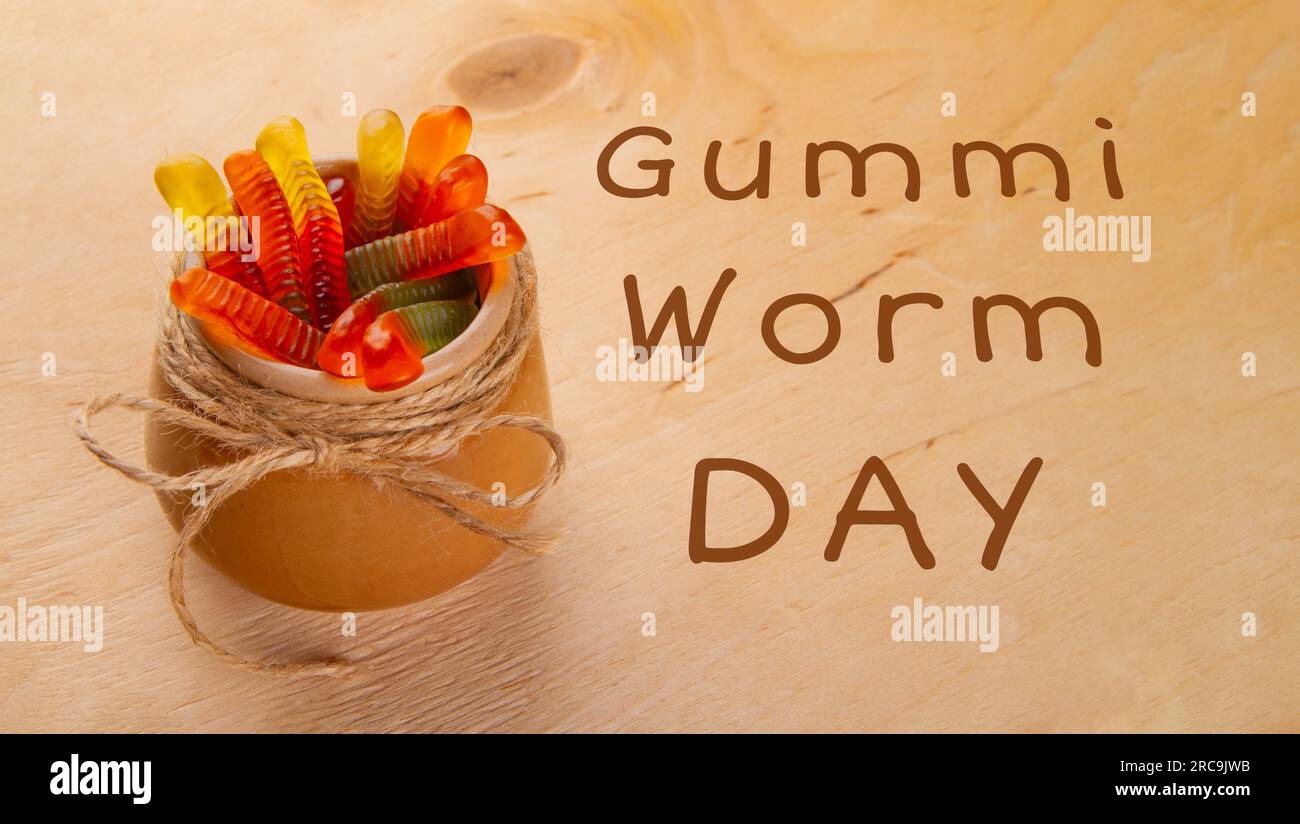 Gummi worms on beige wooden background with text: "Gummi worm day Stock ...