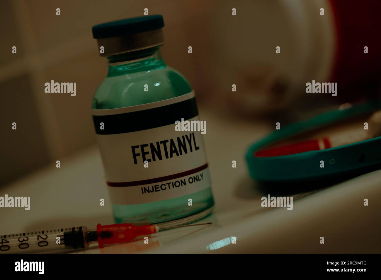 closeup of a simulated vial of fentanyl and a syringe on a toilet ...