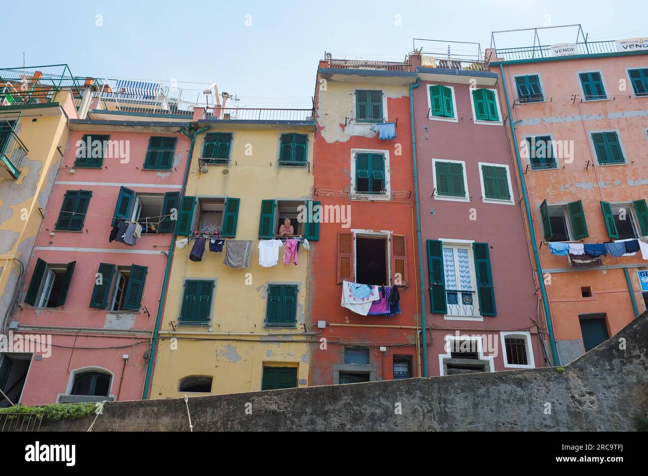 Cinque Terre, Italy - woman watches from one window of colorful houses ...