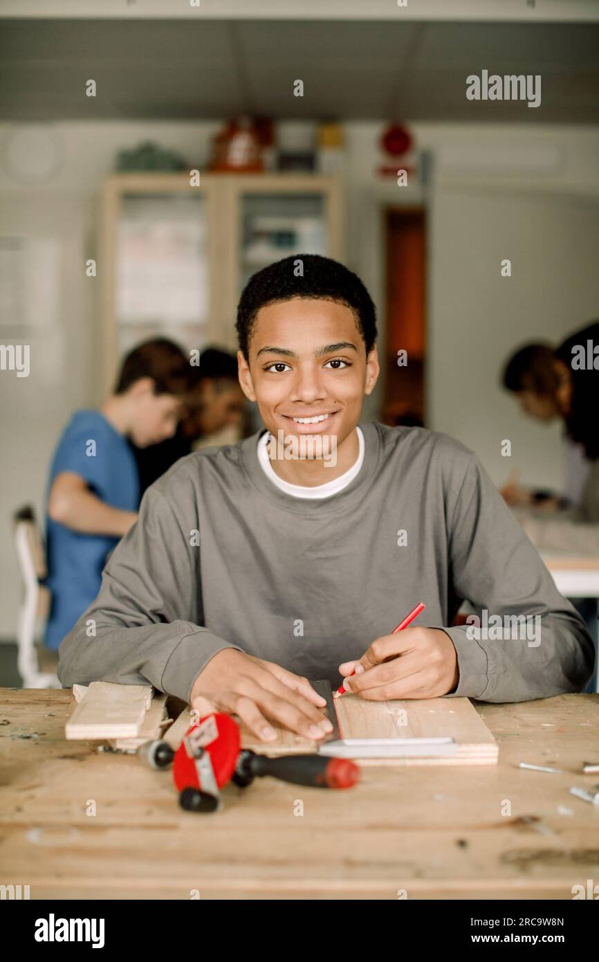 Portrait of smiling male teenage student with ruler and pencil during ...
