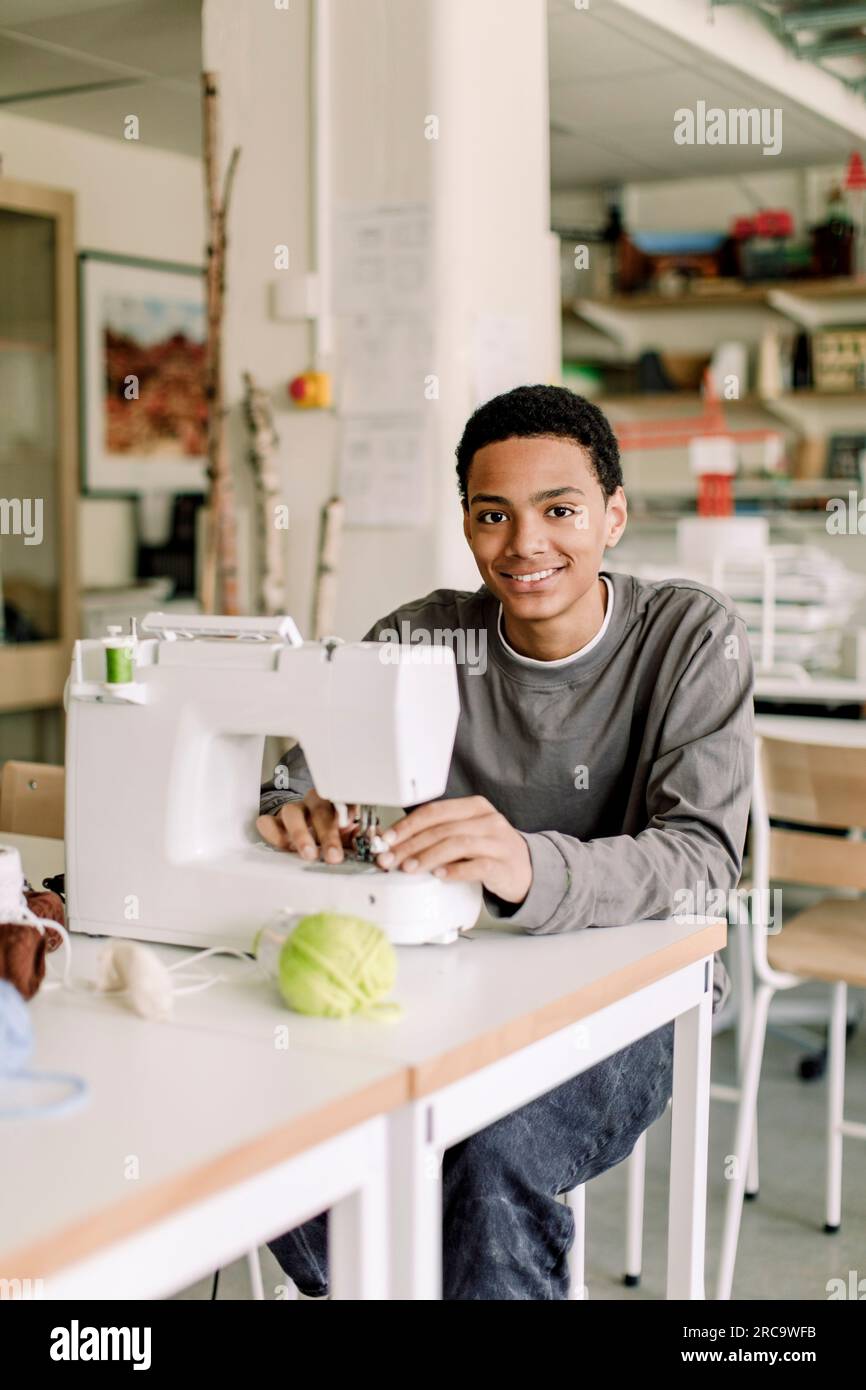 Portrait of smiling teenage male student during sewing class at high ...