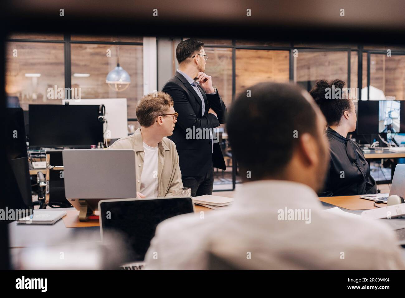 Business manager and colleagues looking at computer monitor during ...