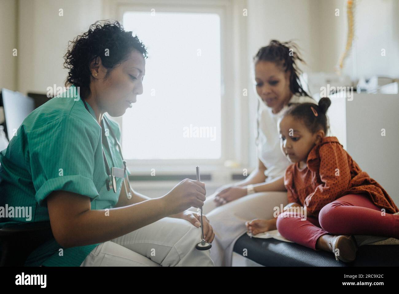 Female pediatric holding reflex hammer discussing with patient in ...