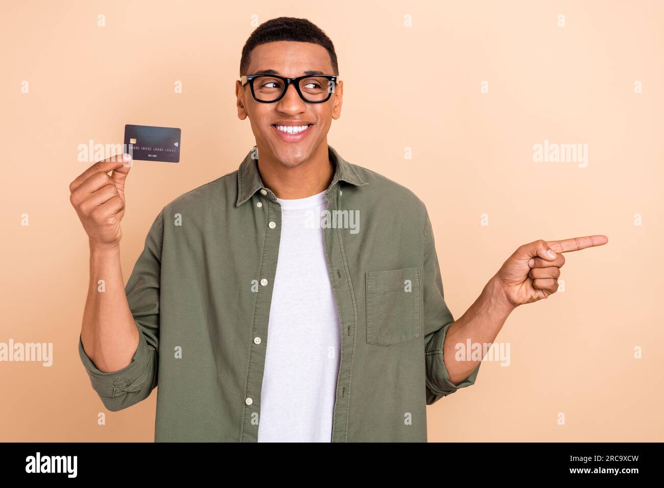 Photo of cheerful handsome guy hand hold debit card look direct finger ...