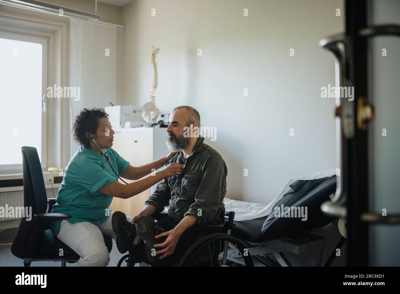 Female doctor examining man with disability in clinic Stock Photo - Alamy