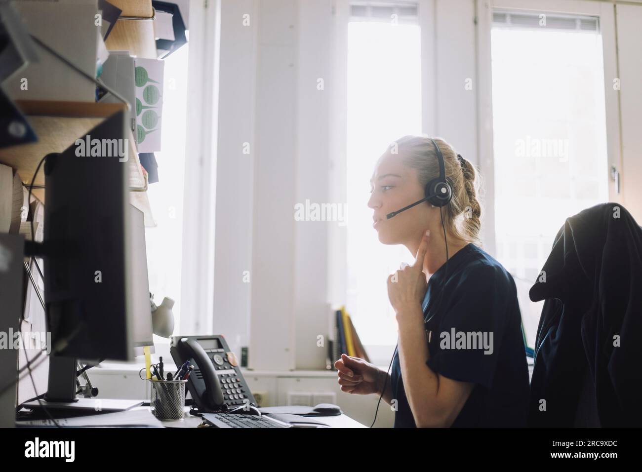 Female healthcare worker consulting on video call through computer at ...