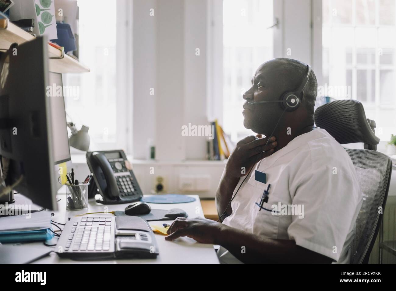 Mature male healthcare worker assisting patient on video call through ...