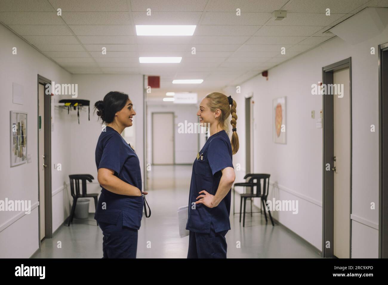 Side view of smiling female medical staff talking with each other while ...