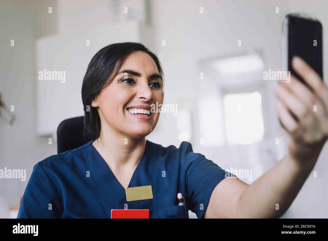Happy female nurse doing video call through smart phone at hospital ...