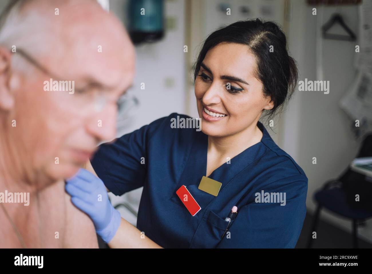 Smiling female nurse doing medical exam of senior patient at hospital ...
