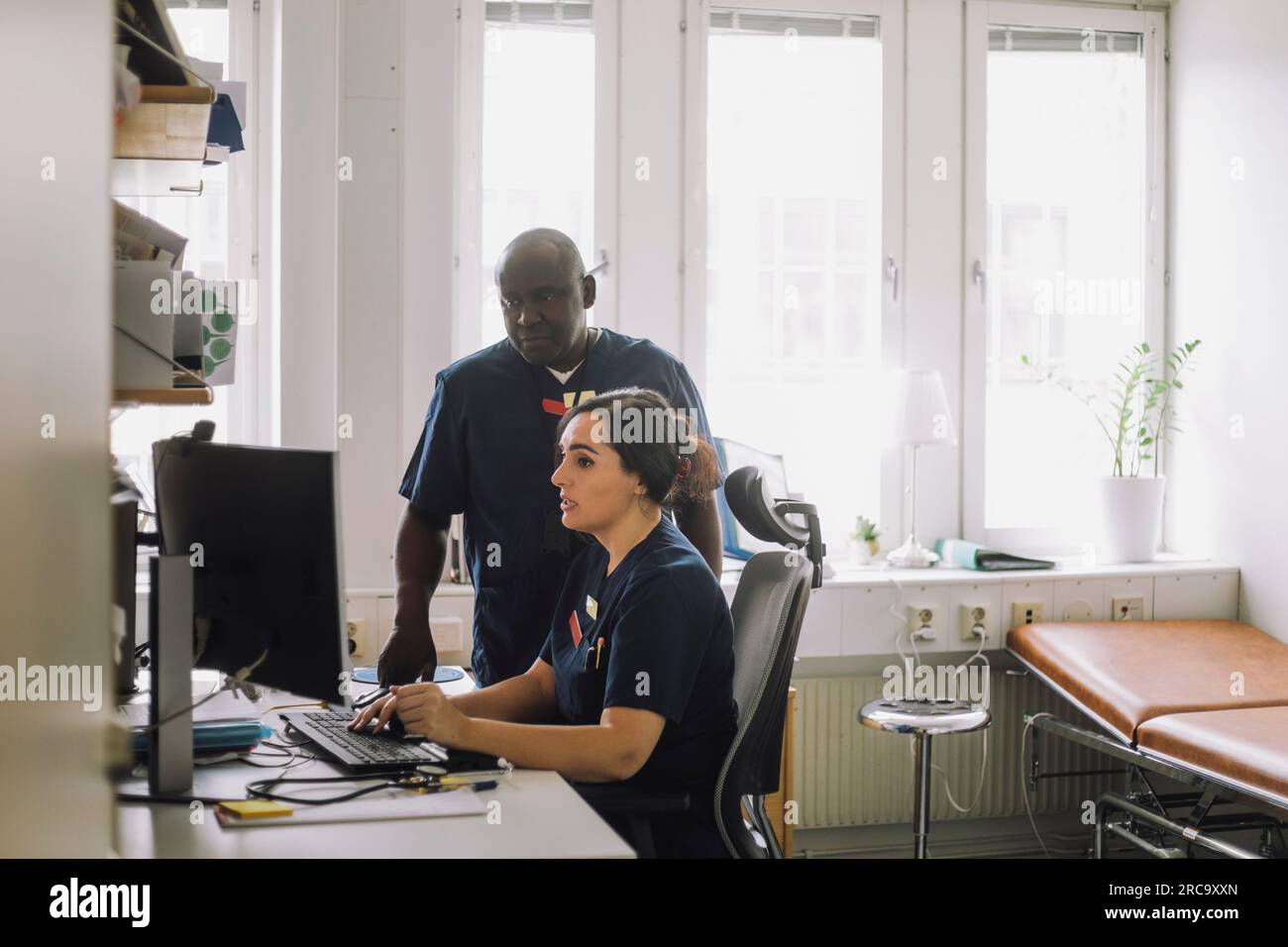 Female nurse explaining colleague over computer at hospital Stock Photo ...