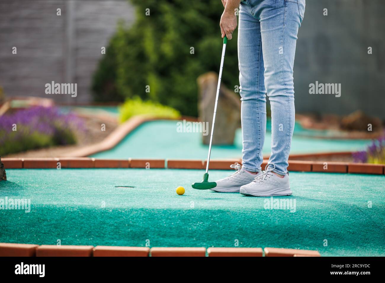 Woman playing mini golf and trying putting ball into hole. Summer ...