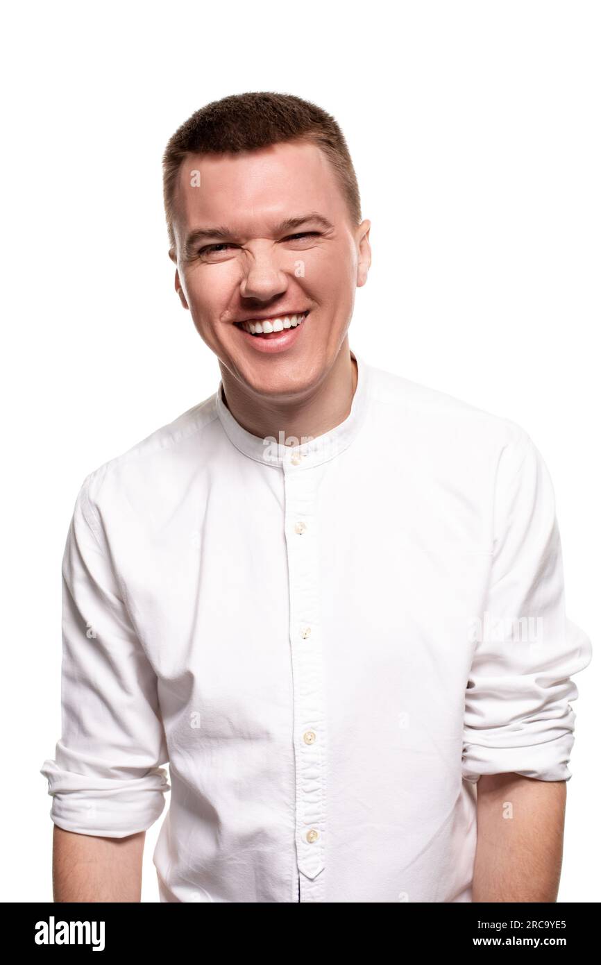 Charming handsome young man in a white shirt is making faces, while ...