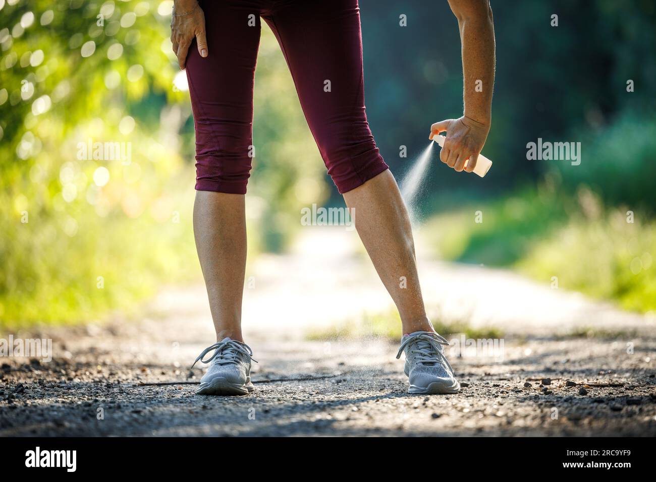 Woman applying insect repellent against mosquito and tick on her leg ...