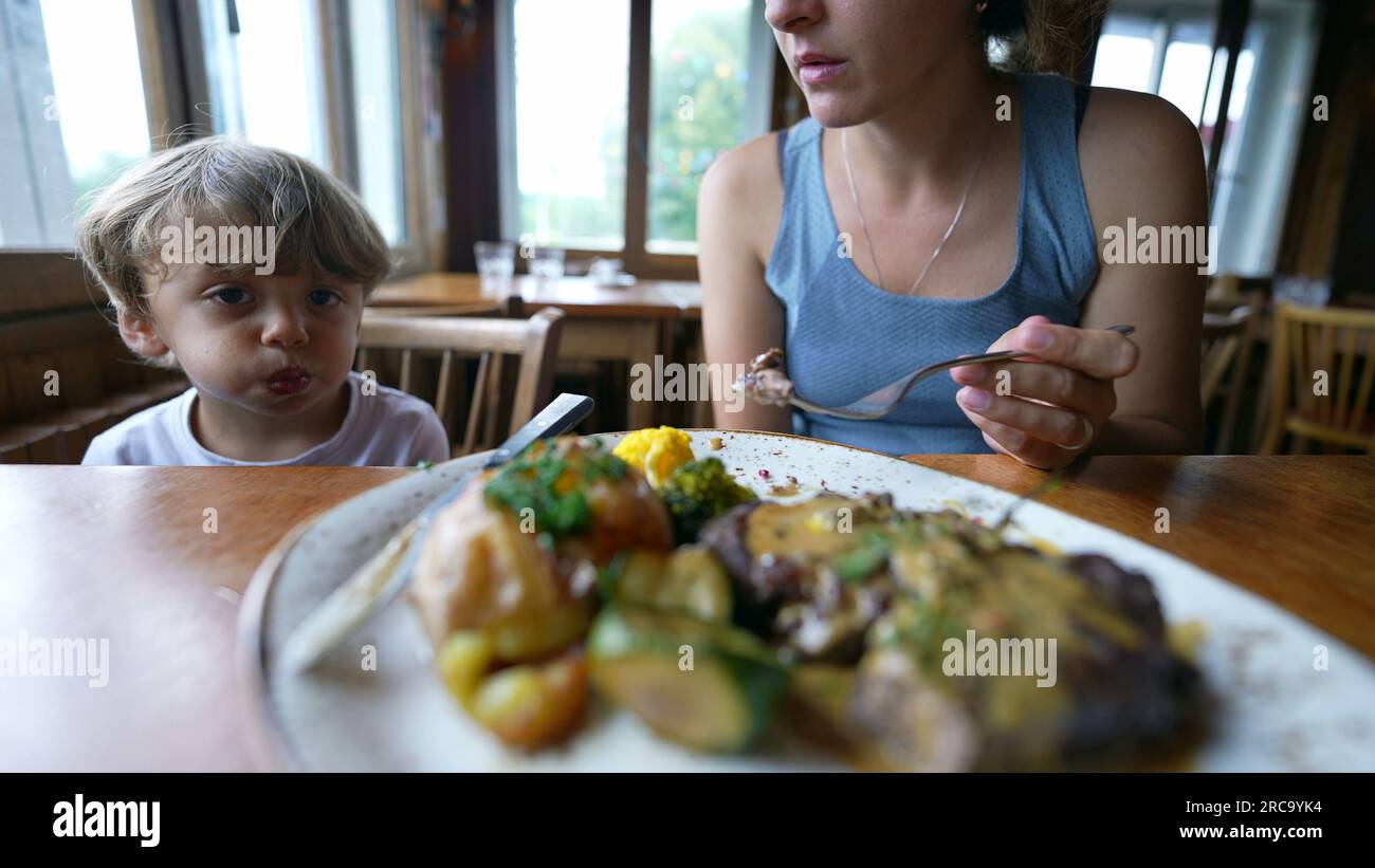 Mother and child sitting at restaurant kid refusing food not wanting to ...